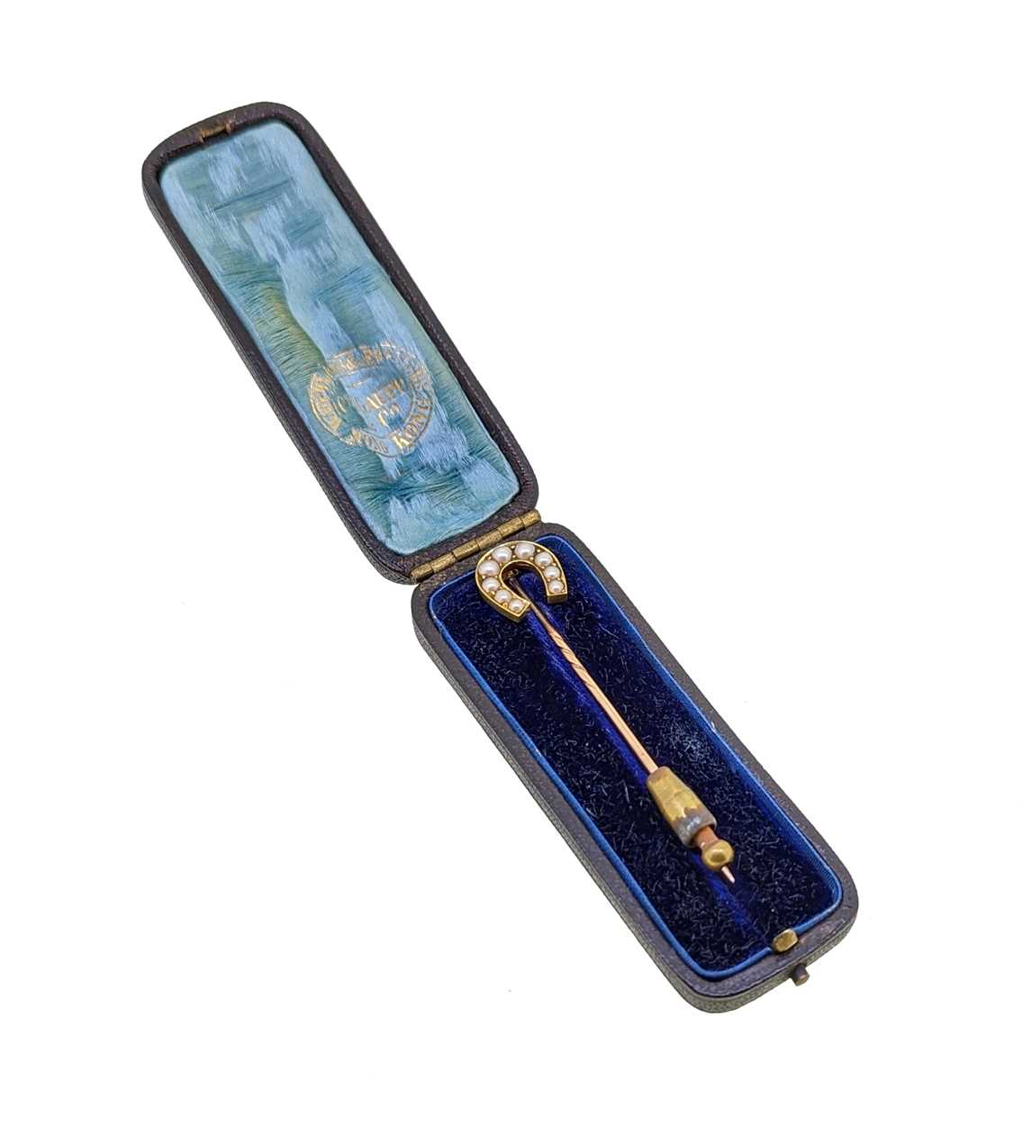 Lot 158 - A split pearl horseshoe stick pin, the